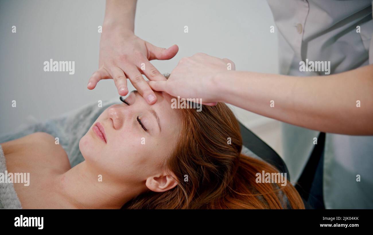 Massage Woman Massage Therapist Massaging The Face Of A Red Haired
