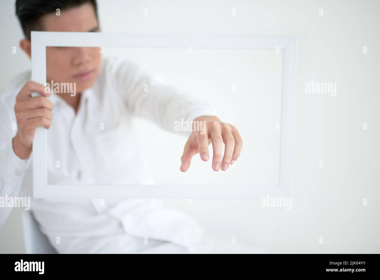 Man putting his hand through the picture frame Stock Photo - Alamy
