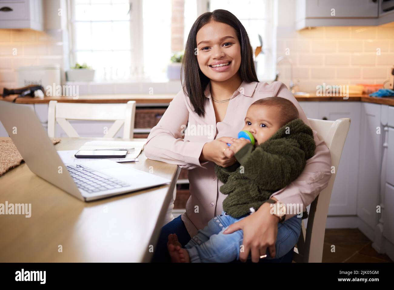 Multi tasking at its best. a young woman using a laptop while caring ...