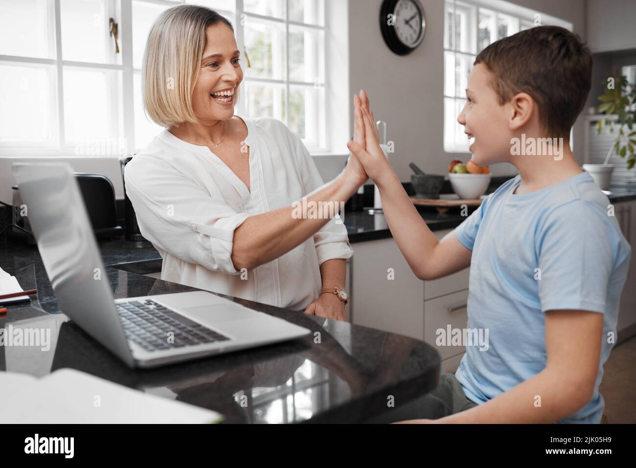 We make a great team. a young mother and her son high fiving while home ...