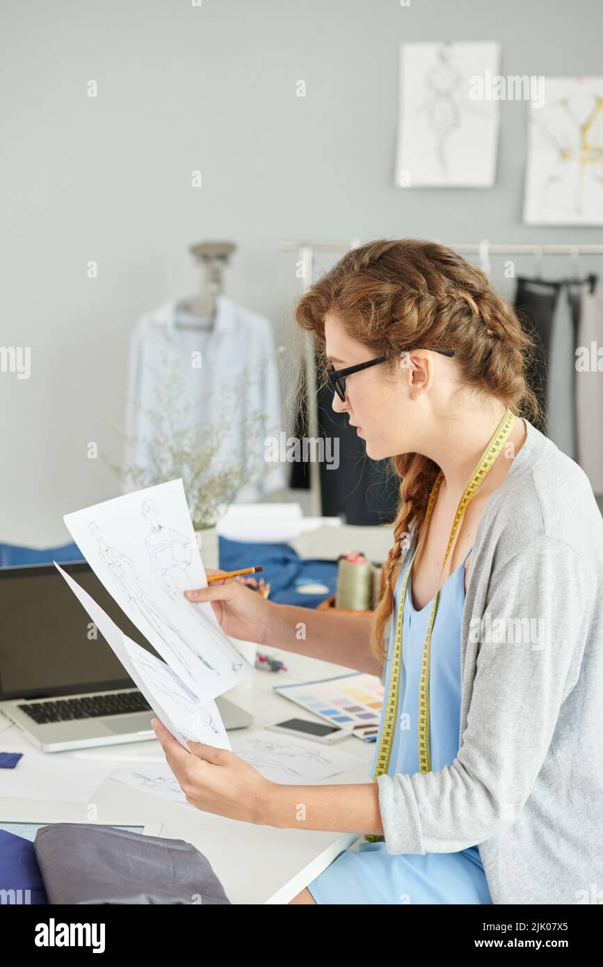 Fashion designer looking at fashion technical drawings in her hands ...