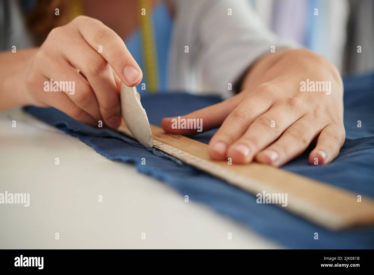 Close-up image of tailor drawing stright line on fabric with white ...