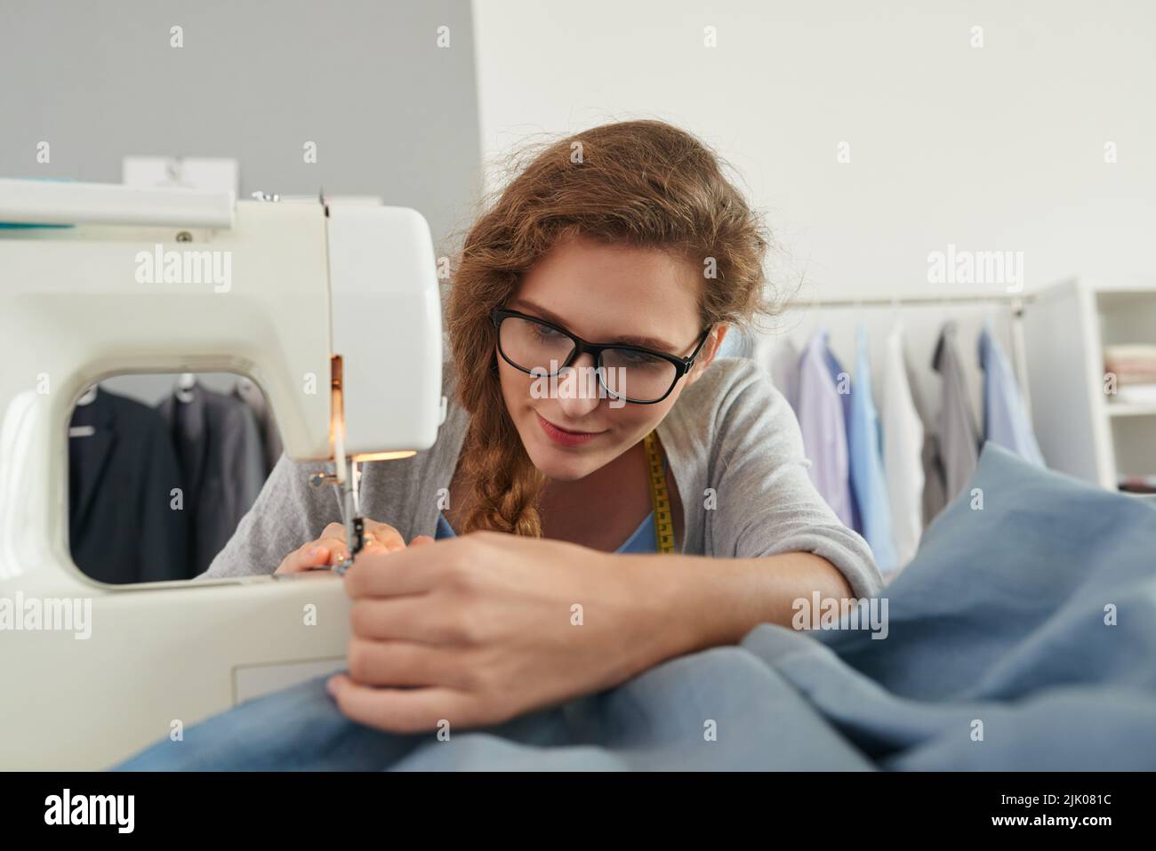 Pretty yong woman enjoying sewing in her studio Stock Photo - Alamy