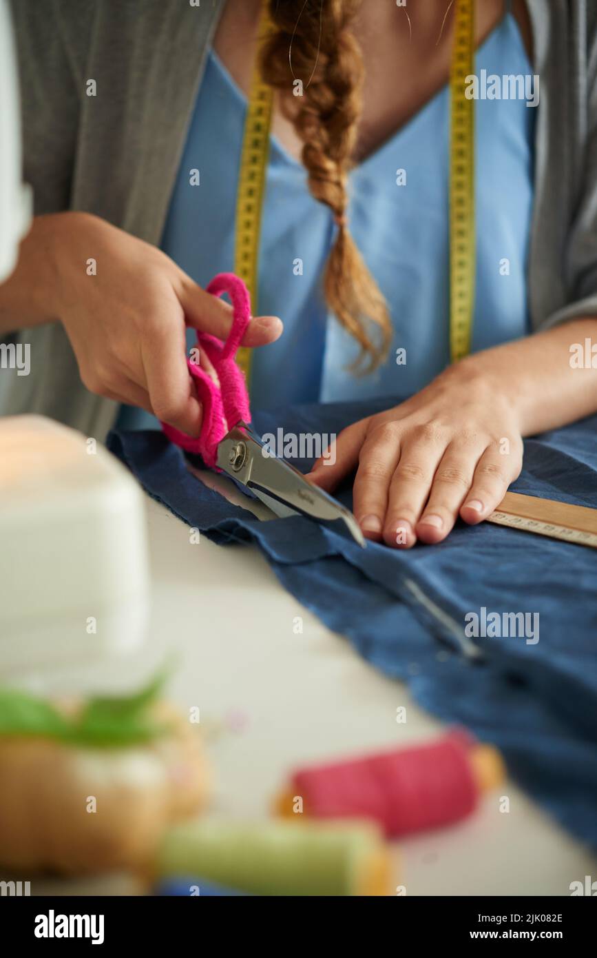 Fashion designer cutting piece of fabric with scissors Stock Photo - Alamy