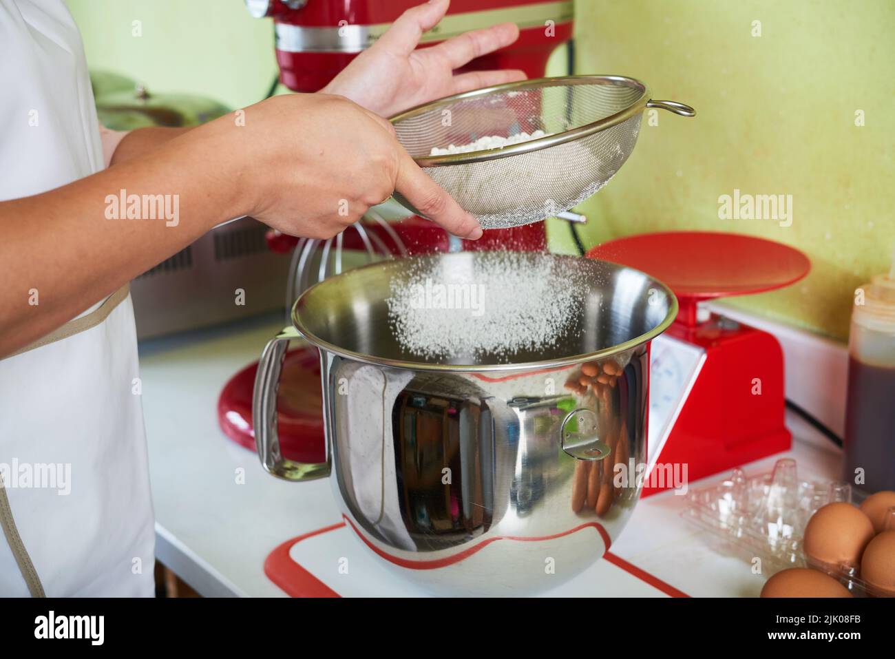 Hands of baker sifting flour into mixer bowl Stock Photo - Alamy