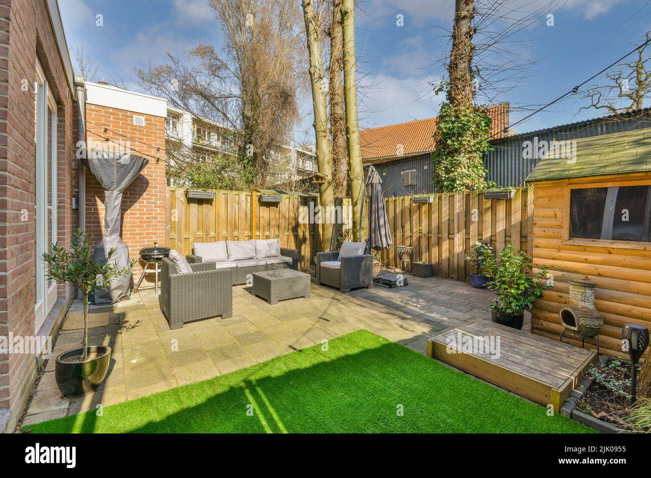 Neat paved patio with sitting area and small garden near wooden fence ...