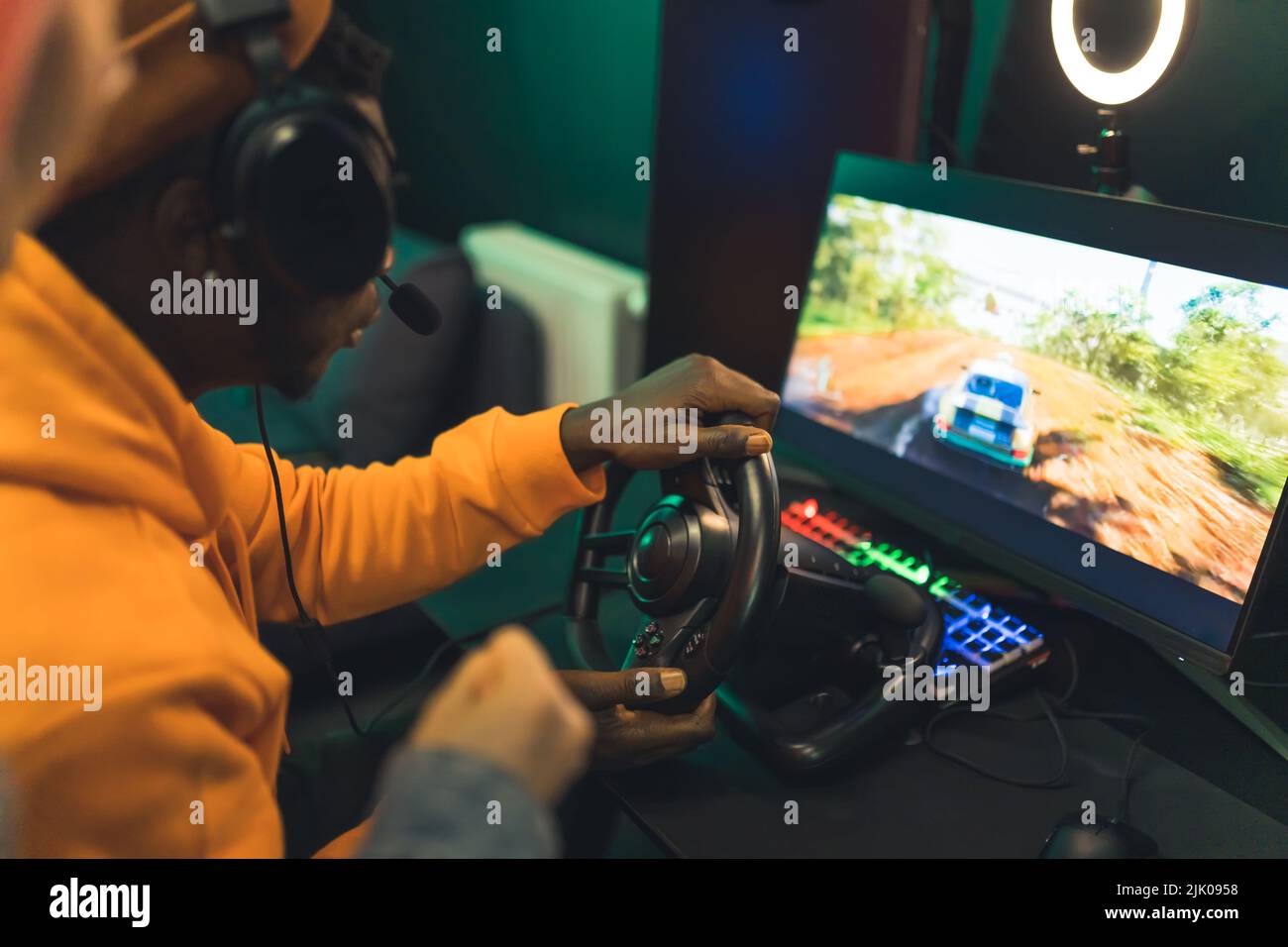 Teenage bluck guy wearing headset playing racing game with steearing ...
