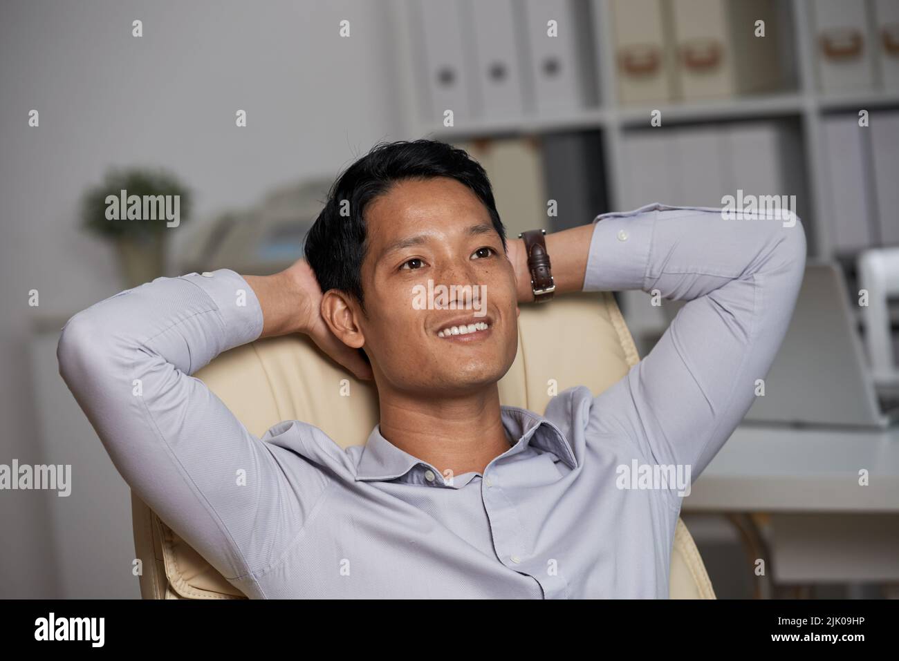 Portrait of dreamy Vietnamese businessman sitting in chair Stock Photo ...
