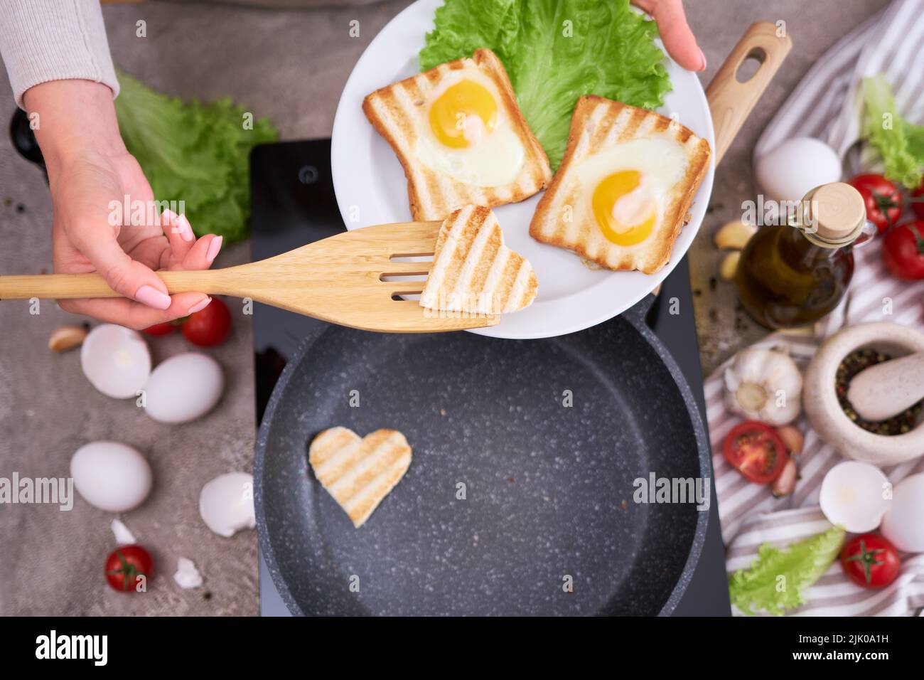 Fried egg Toasts with heart shaped holes on frying pan Stock Photo - Alamy