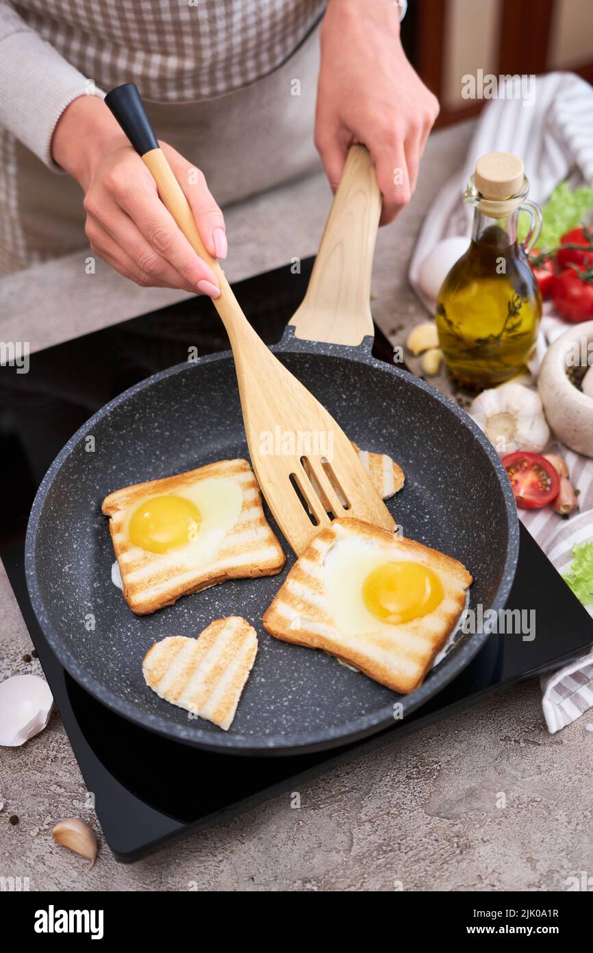 Fried egg Toasts with heart shaped holes on frying pan Stock Photo - Alamy