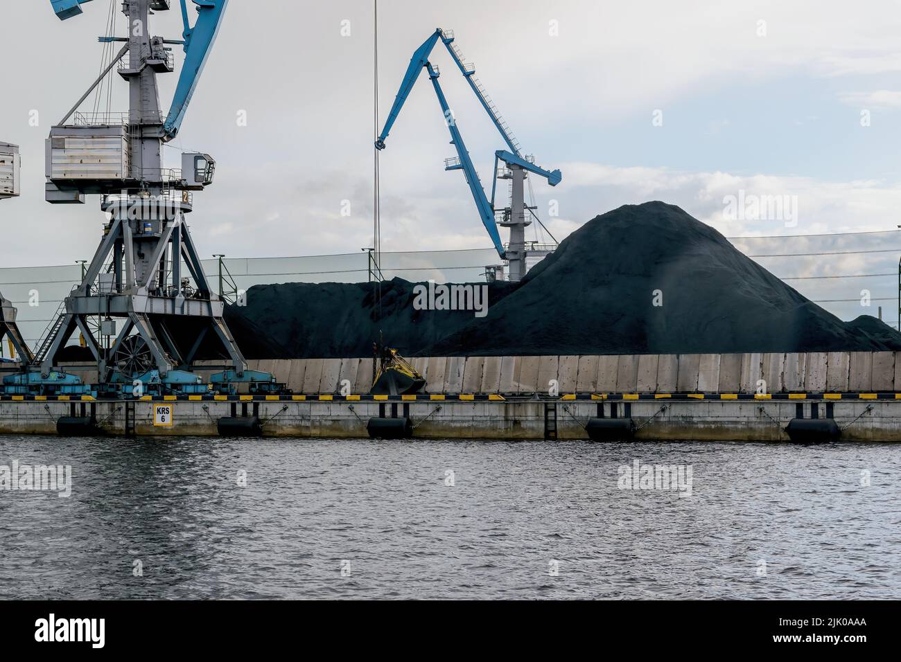 Cargo cranes in the port coal terminal. Pile of coal on the pier Stock ...