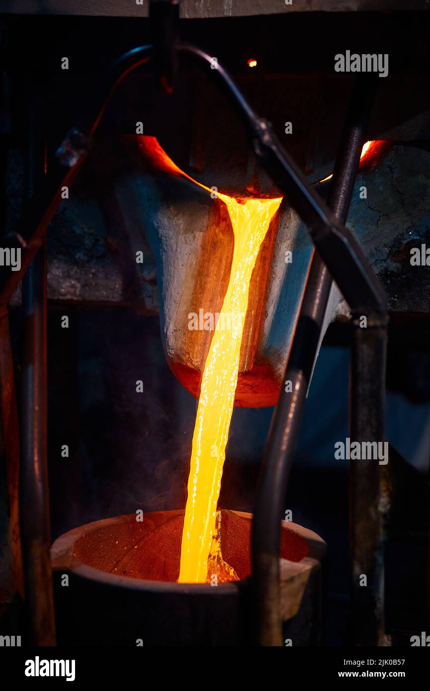 Melted liquid metal flow poured down from pot in furnace Stock Photo ...