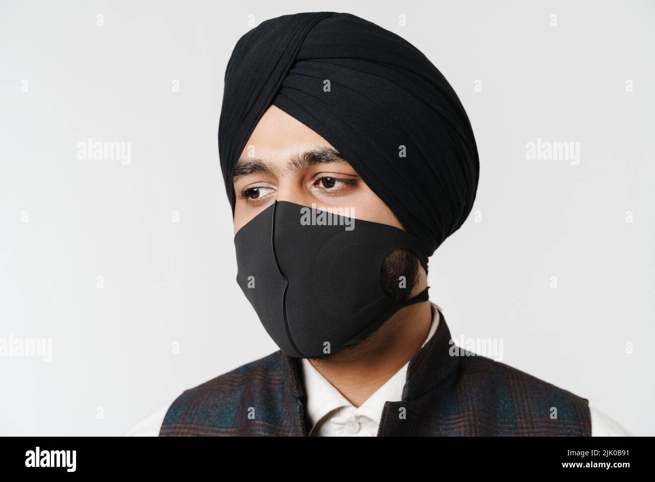 South asian man wearing turban and face mask looking at camera isolated ...