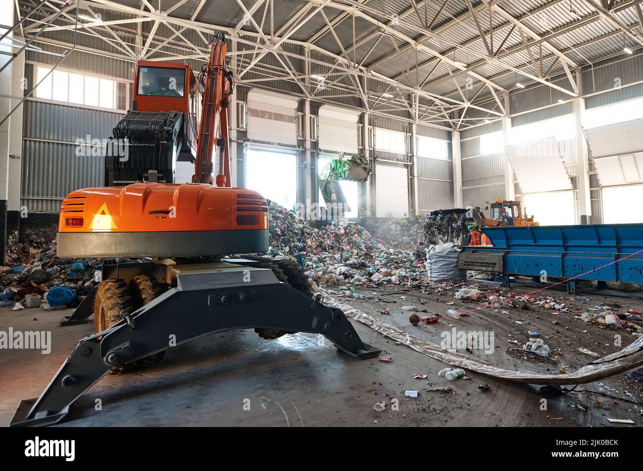Excavator grabs trash in warehouse of waste processing plant Stock ...