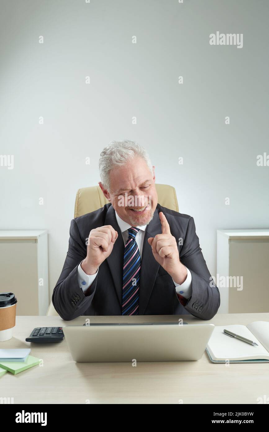 Cheerful mature manager looking on computer screen with wide smile and ...