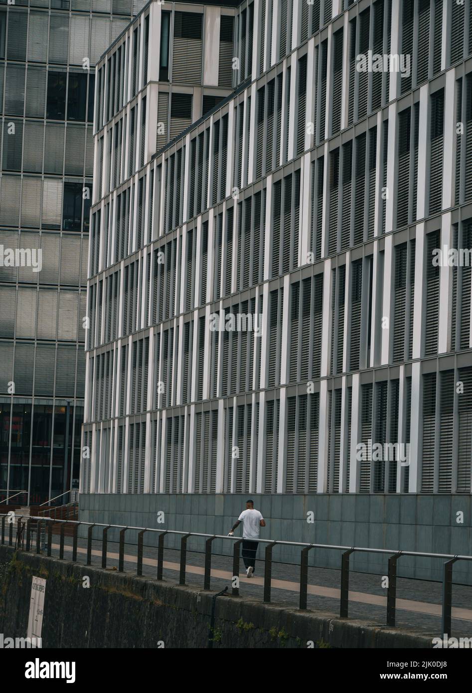 A person walking by a building with modern facade Stock Photo - Alamy
