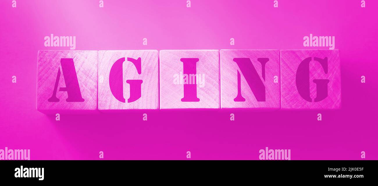 Aging - word from wooden blocks with letters, on red background ...