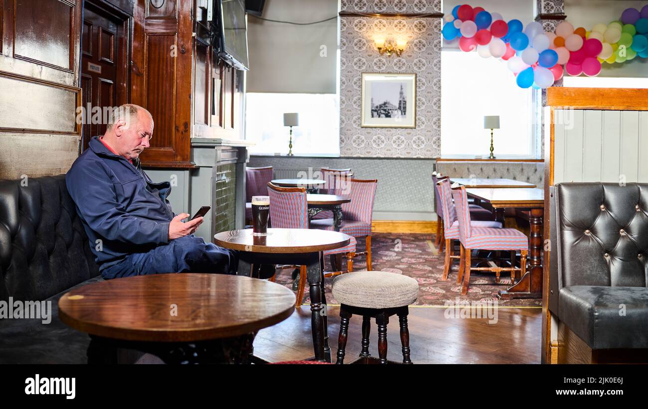 Man in typical english pub on mobile phone with pint of guiness Stock ...