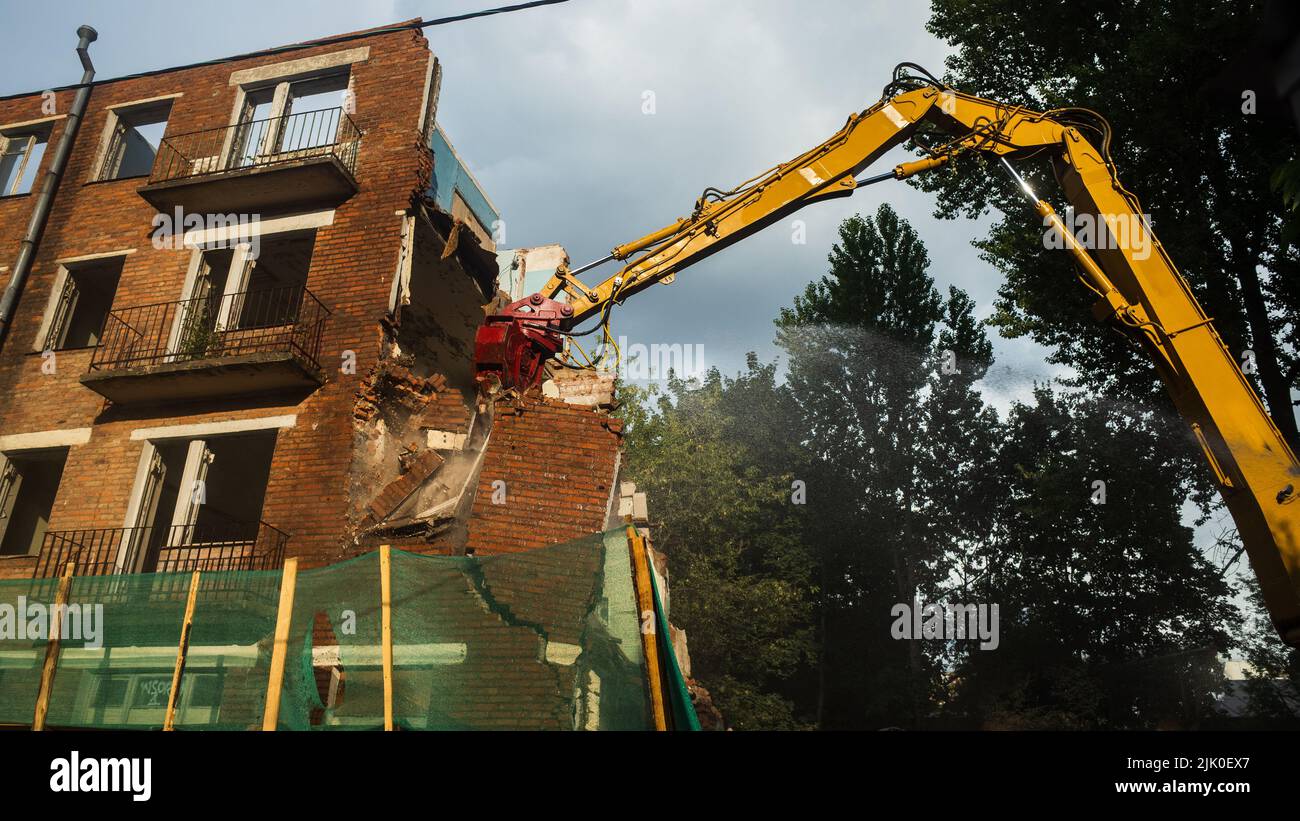Demolition of a brick building with excavator mechanical arm ...
