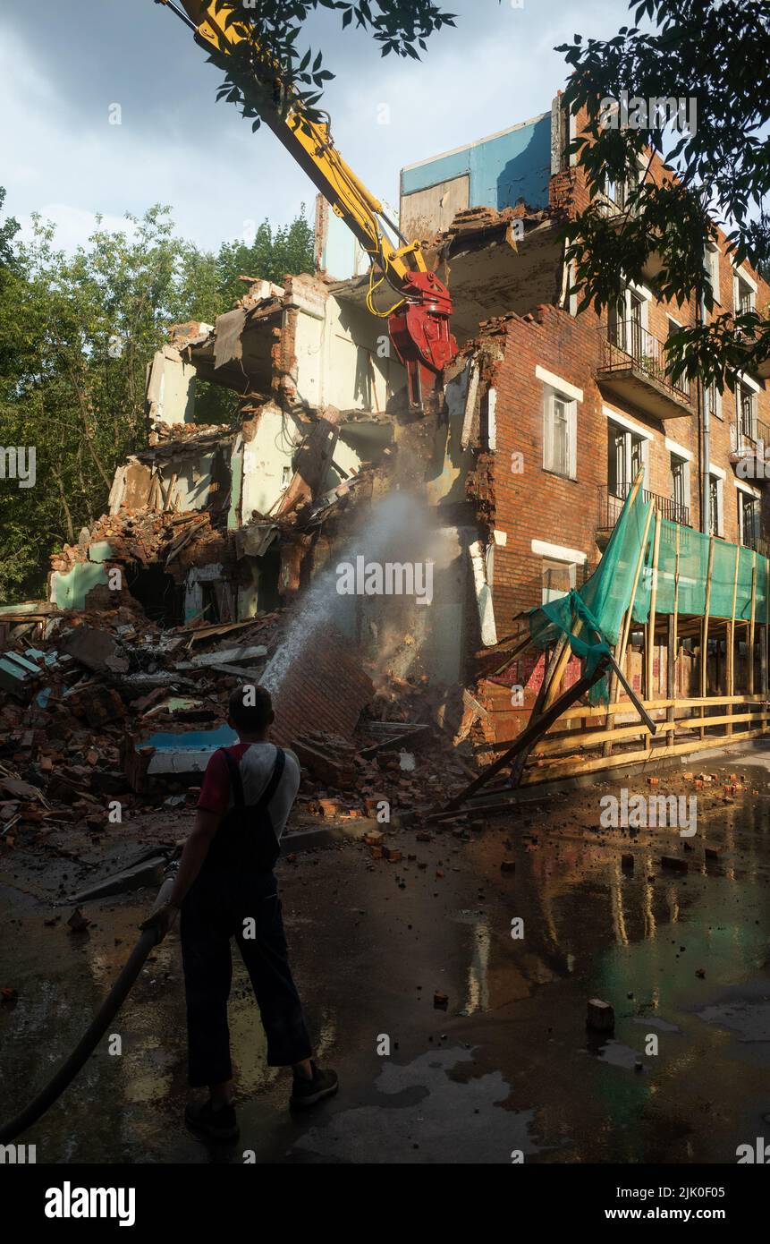 Demolition of a brick building with excavator mechanical arm ...