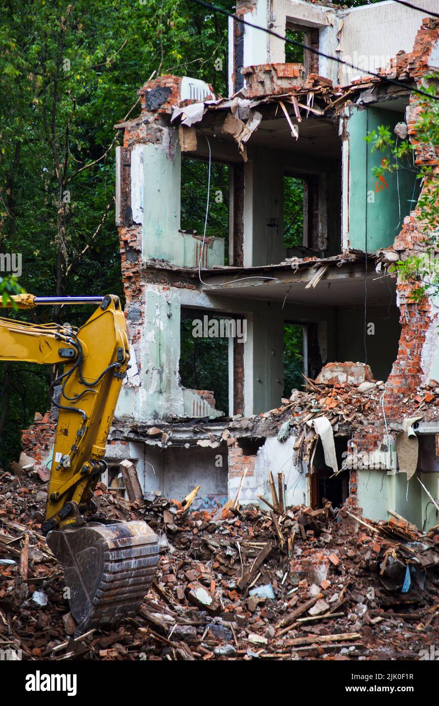 Demolition of a brick building with excavator mechanical arm ...