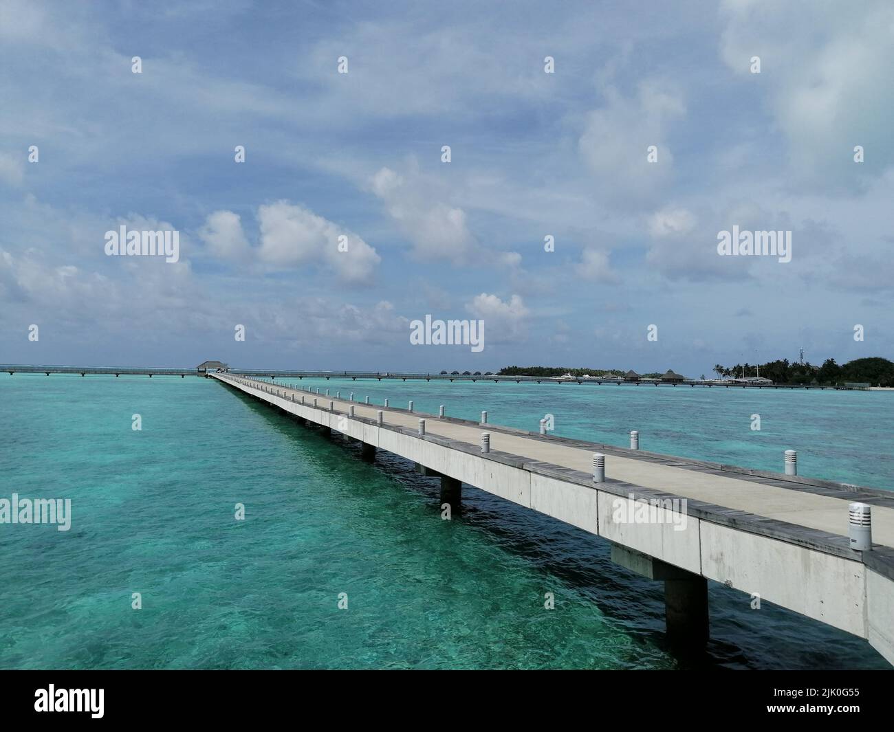 A long concrete bridge over the tranquil sea water under blue sky in ...