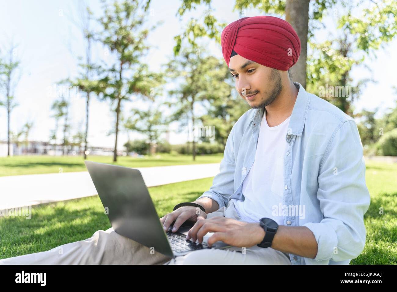 Male Indian student wearing red traditional national turban using ...