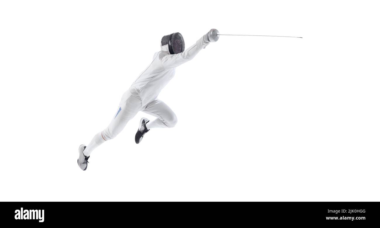 Dynamic portrait of young man, fencer in in fencing costume with sword ...