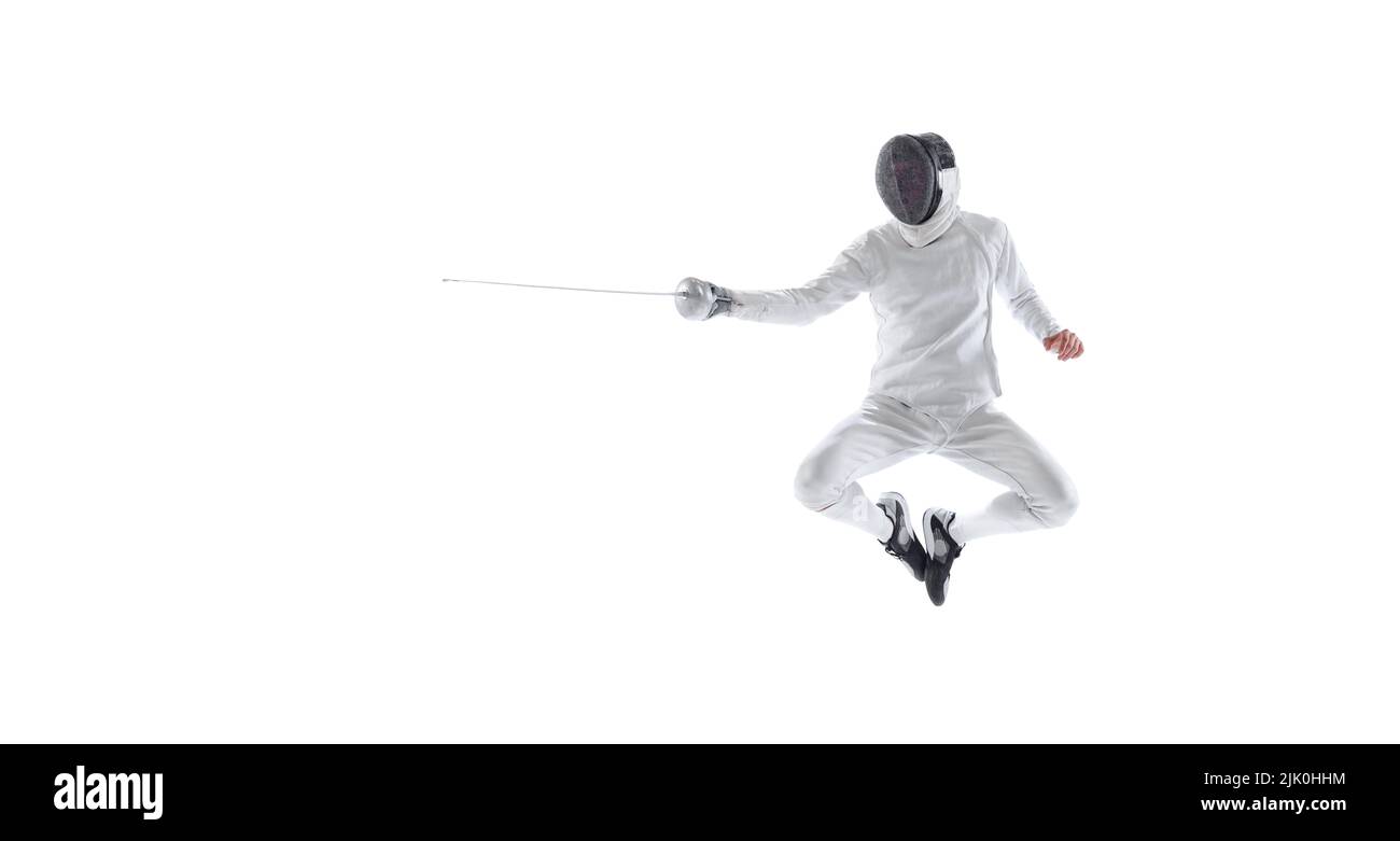 Dynamic portrait of young man, fencer in in fencing costume with sword ...