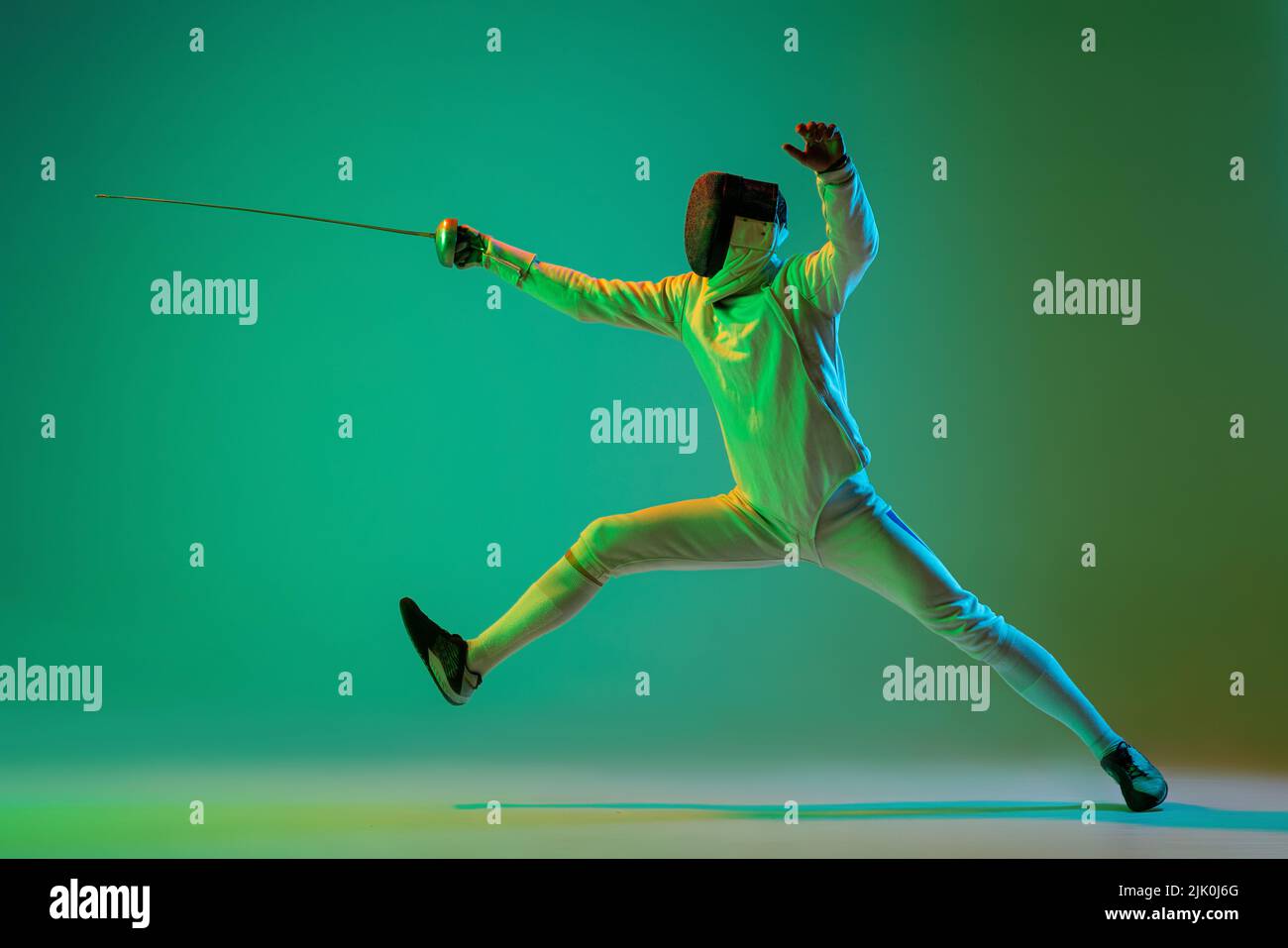 Studio shot of young man, fencer with smallsword practicing fencing ...