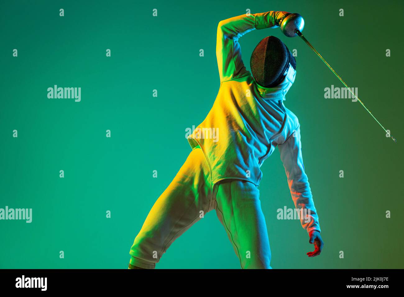 Studio shot of young man, fencer with smallsword practicing fencing ...
