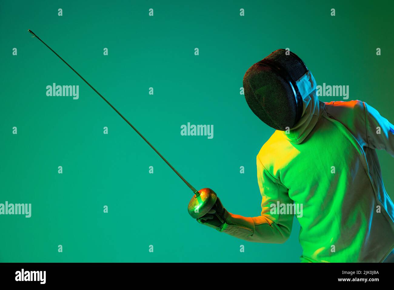 Studio shot of young man, fencer with smallsword practicing fencing ...