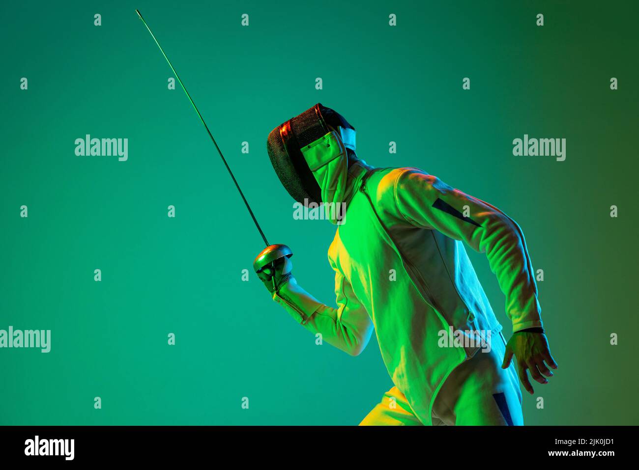 Studio shot of young man, fencer with smallsword practicing fencing ...