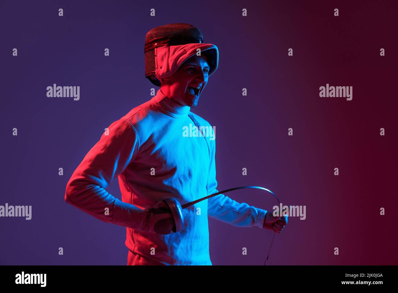 Portrait of young tall male fencer in fencing costume and mask holding ...