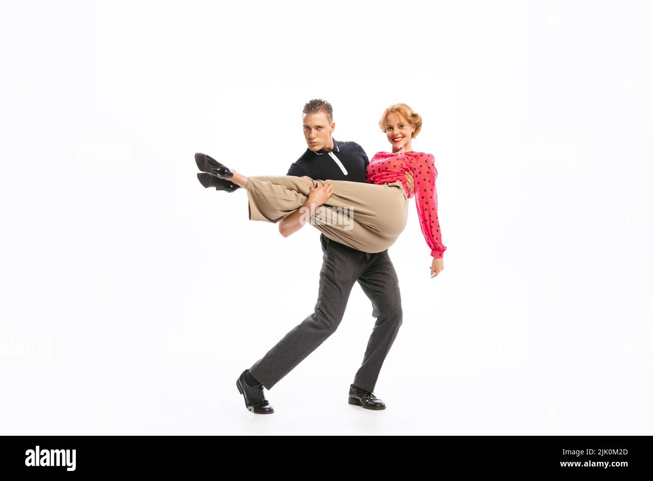 Portrait of stylish young couple, man and woman dancing isolated over ...