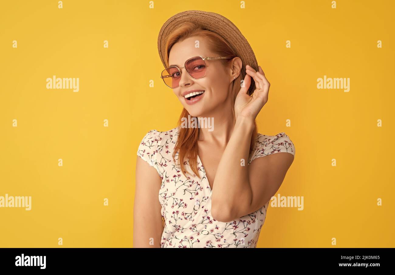 cheerful young woman in straw hat and sunglasses on yellow background ...