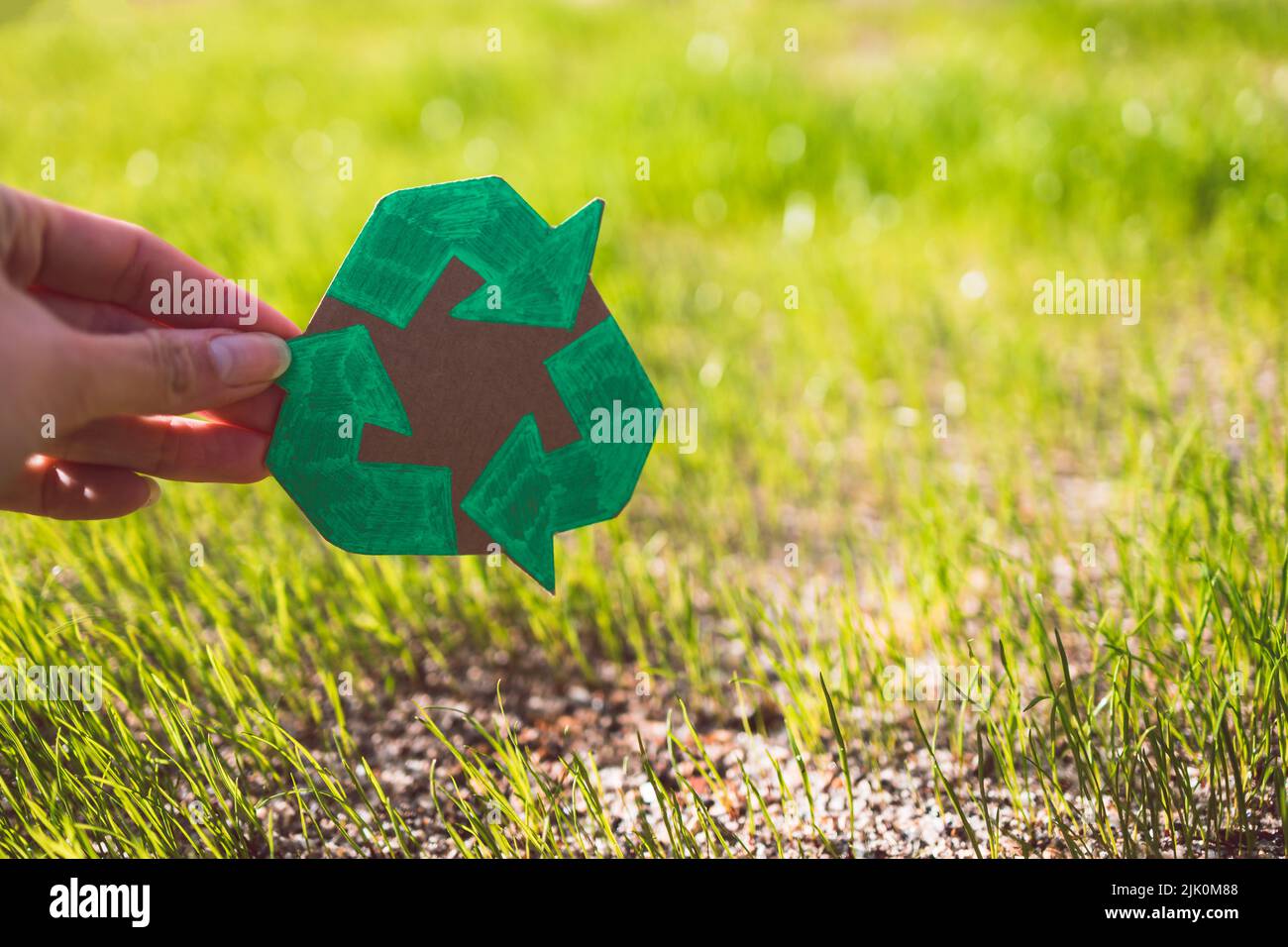 recycle sign hand drawn on cardboard over green grass under the ...