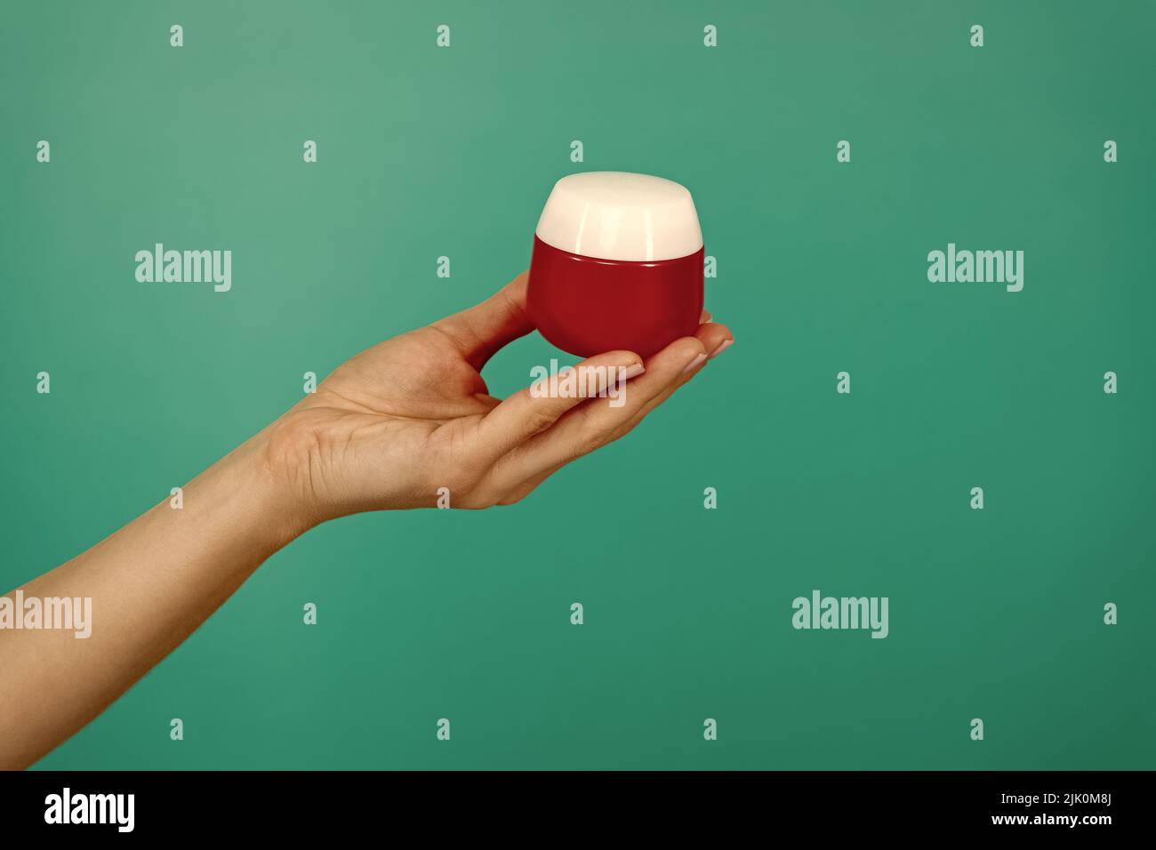 female hand hold skin cream on blue background Stock Photo - Alamy