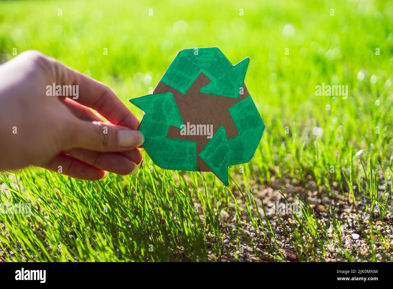 recycle sign hand drawn on cardboard over green grass under the ...