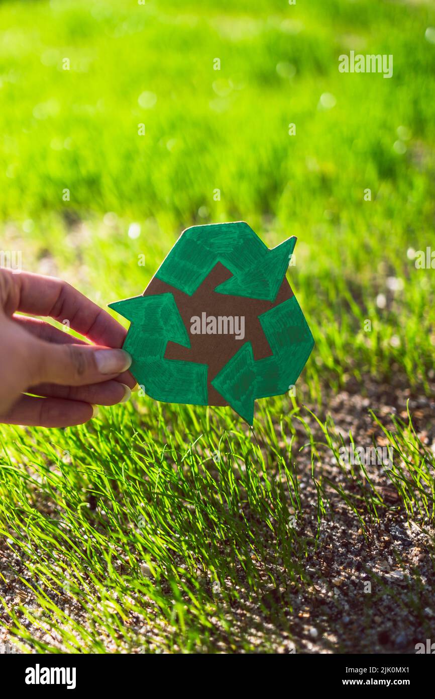 recycle sign hand drawn on cardboard over green grass under the ...