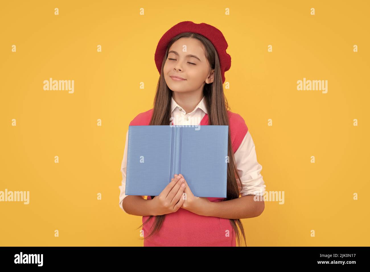 dreamy teen school girl in french beret reading book on yellow ...