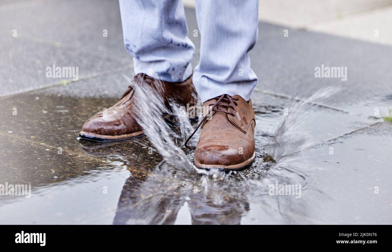 Watch your step. a unrecognizable man walking in a puddle of water ...