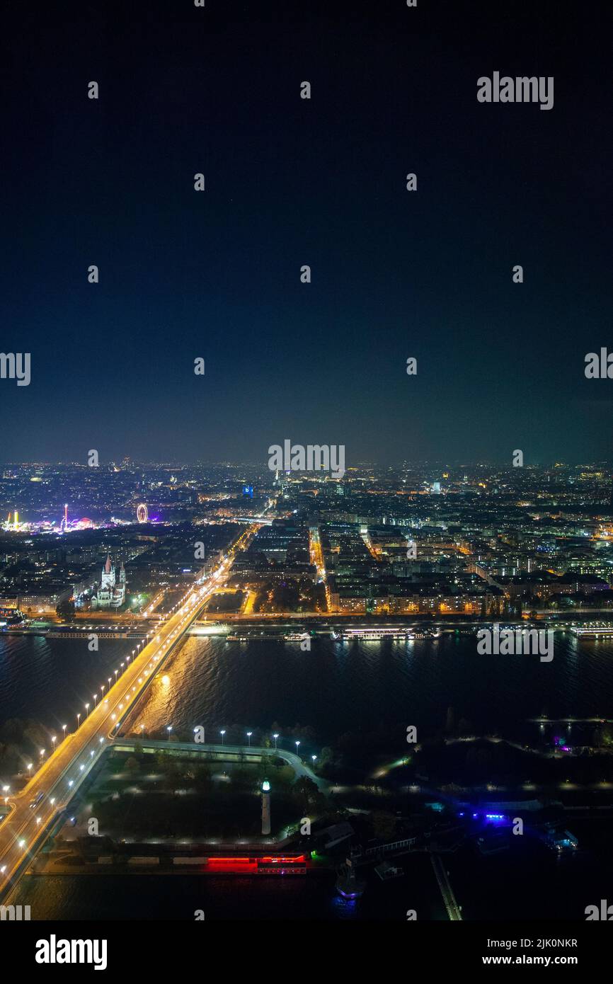 An aerial view of illuminated cityscape with long bridge over the river ...