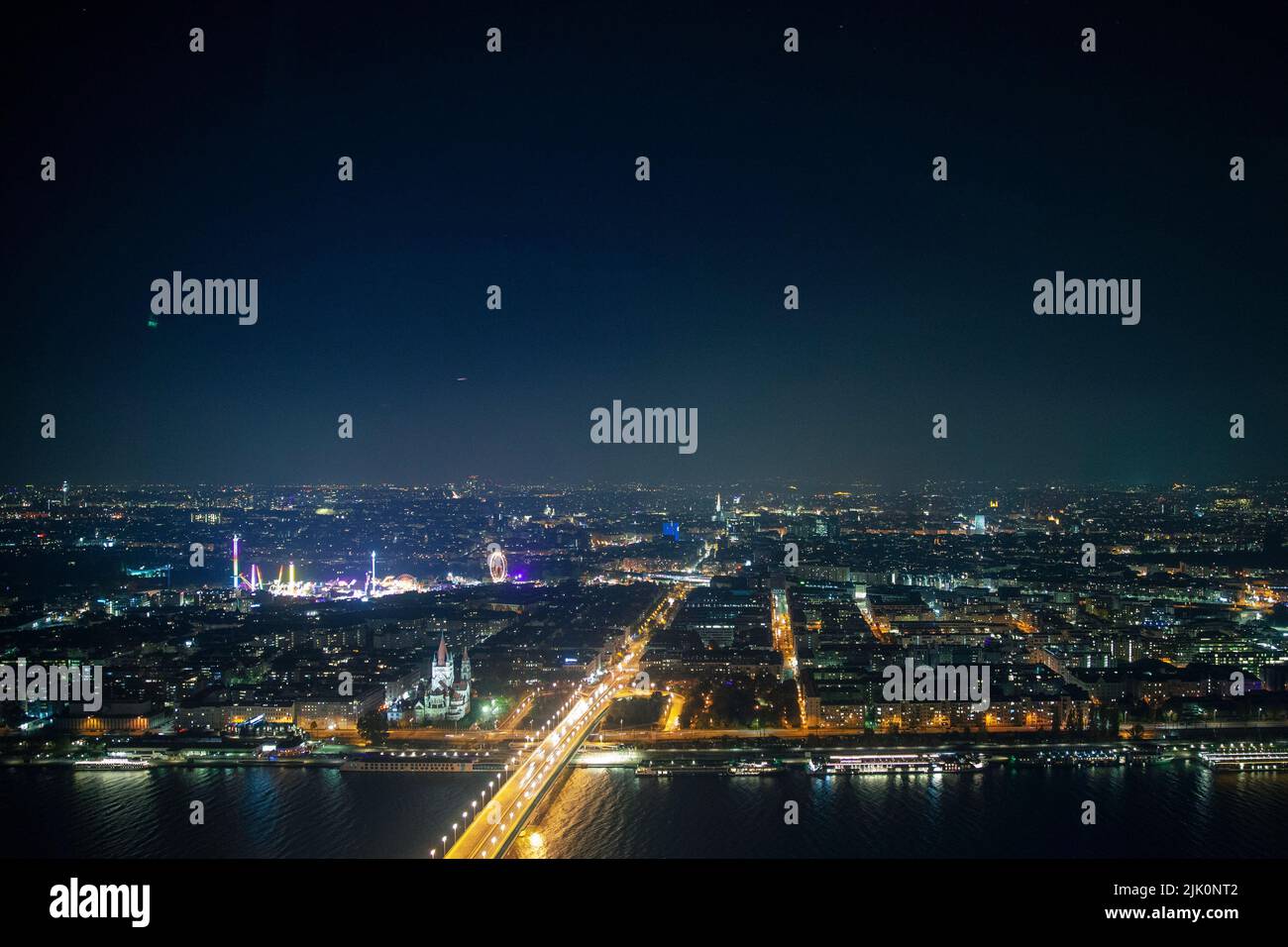An aerial view of illuminated cityscape with long bridge over the river ...