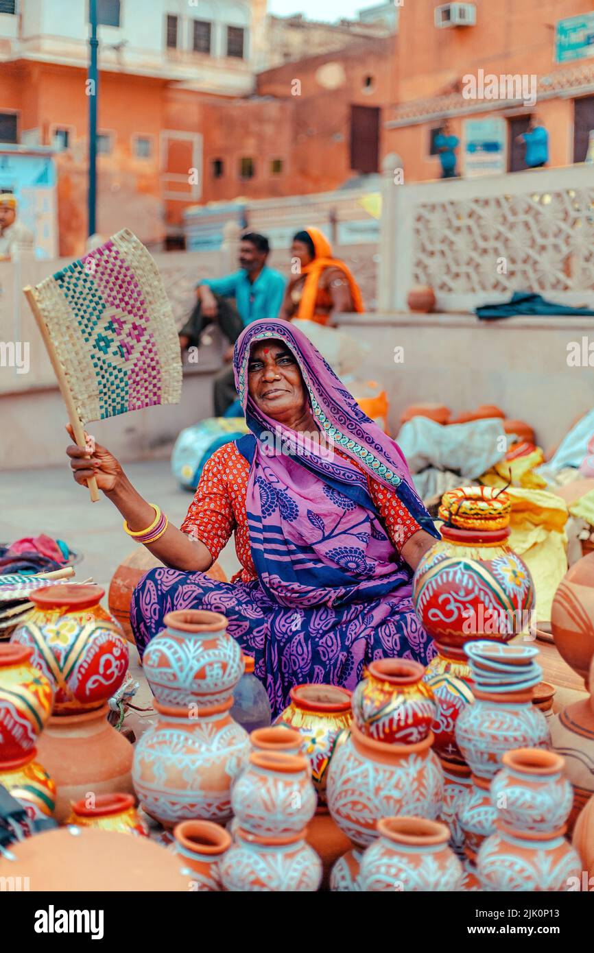 A senior Indian woman in traditional clothing selling pottery on the ...