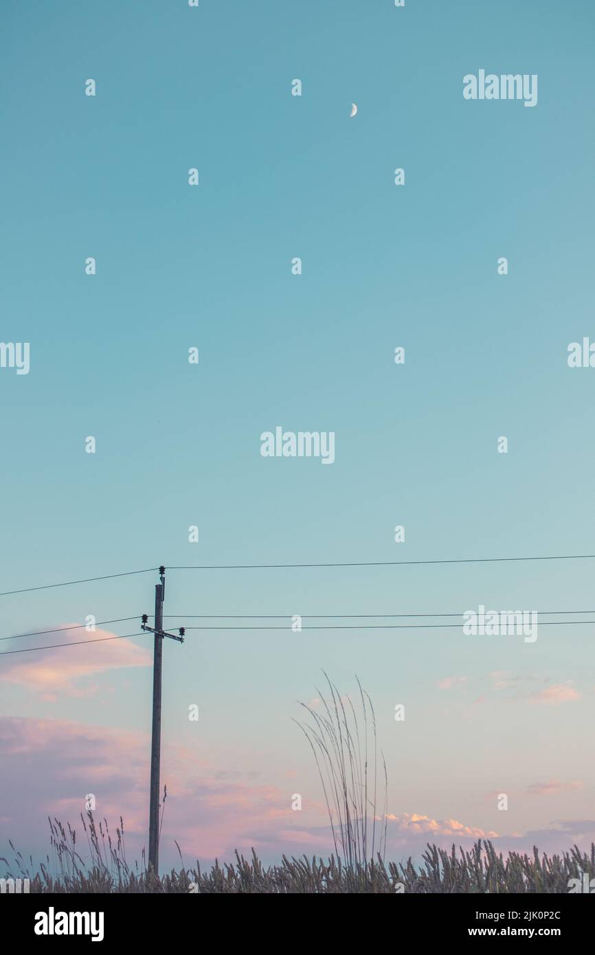 A vertical shot of electric post against blue cloudy sunset sky with ...