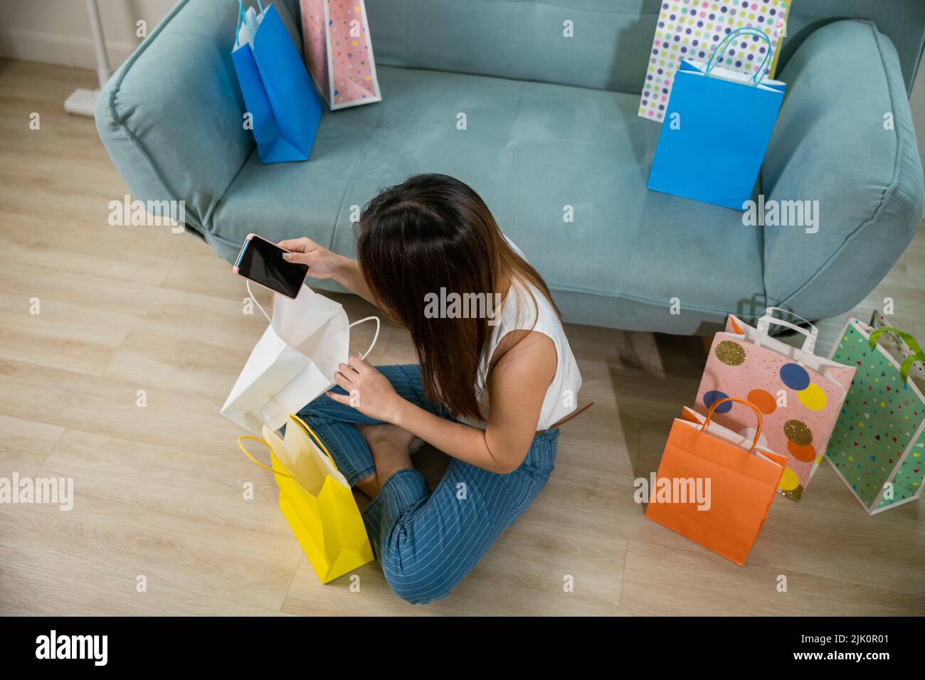 Excited Asian buying woman holding mobile phone with many shopping bags ...