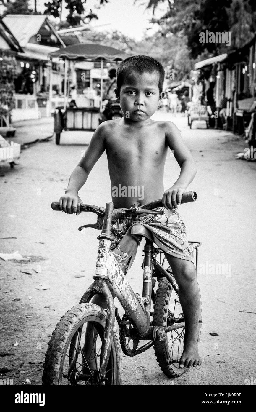 A vertical shot of a child with a bike in the streets of Sea Gypsy ...