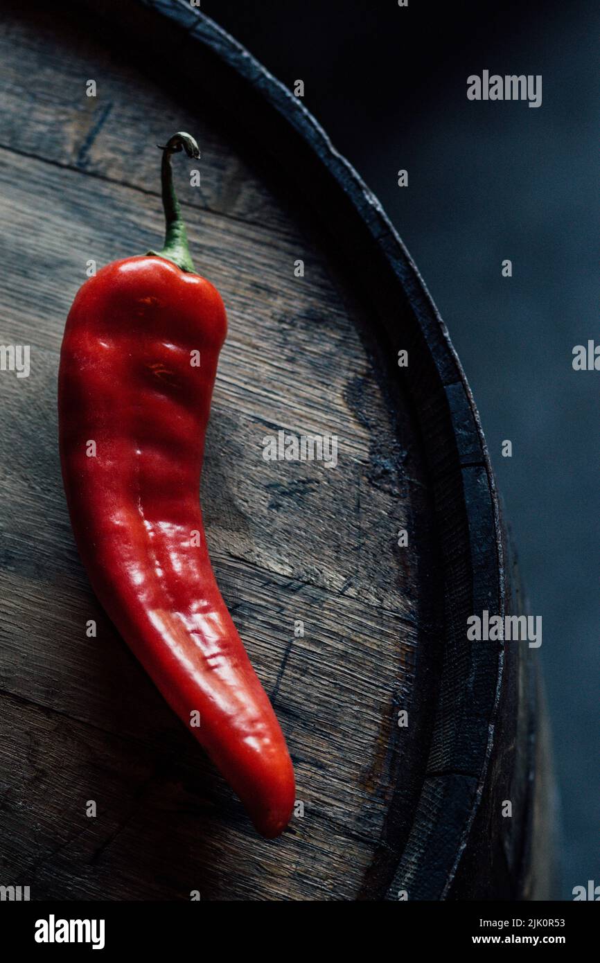 a single red Hungarian goat horn chili pepper on a wooden whiskey ...