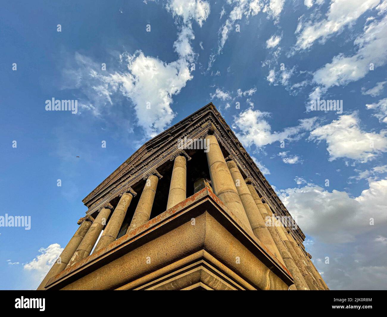 A beautiful ancient Hellenic temple with columns with a cloudy sky on ...